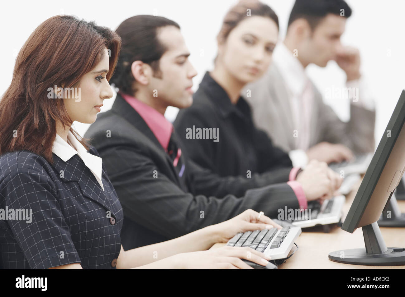 Two businessmen and two businesswomen sitting in front of computers ...