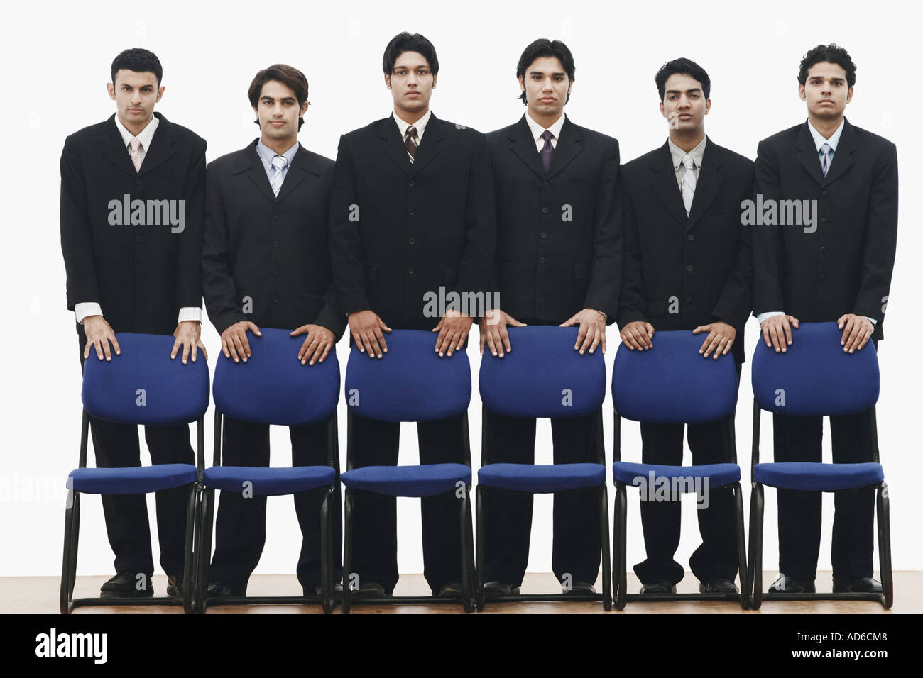 Portrait of a group of young men standing behind chairs Stock Photo - Alamy