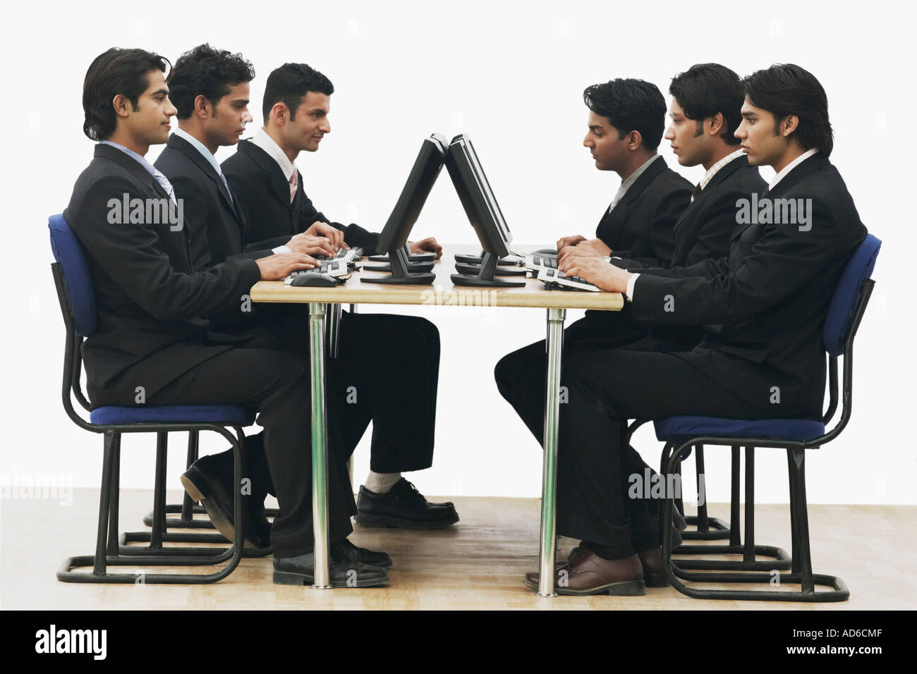 Side profile of a group of businessmen working on computers in an ...