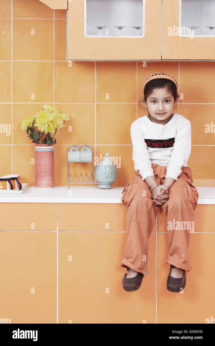Portrait of a girl sitting on a kitchen counter Stock Photo - Alamy