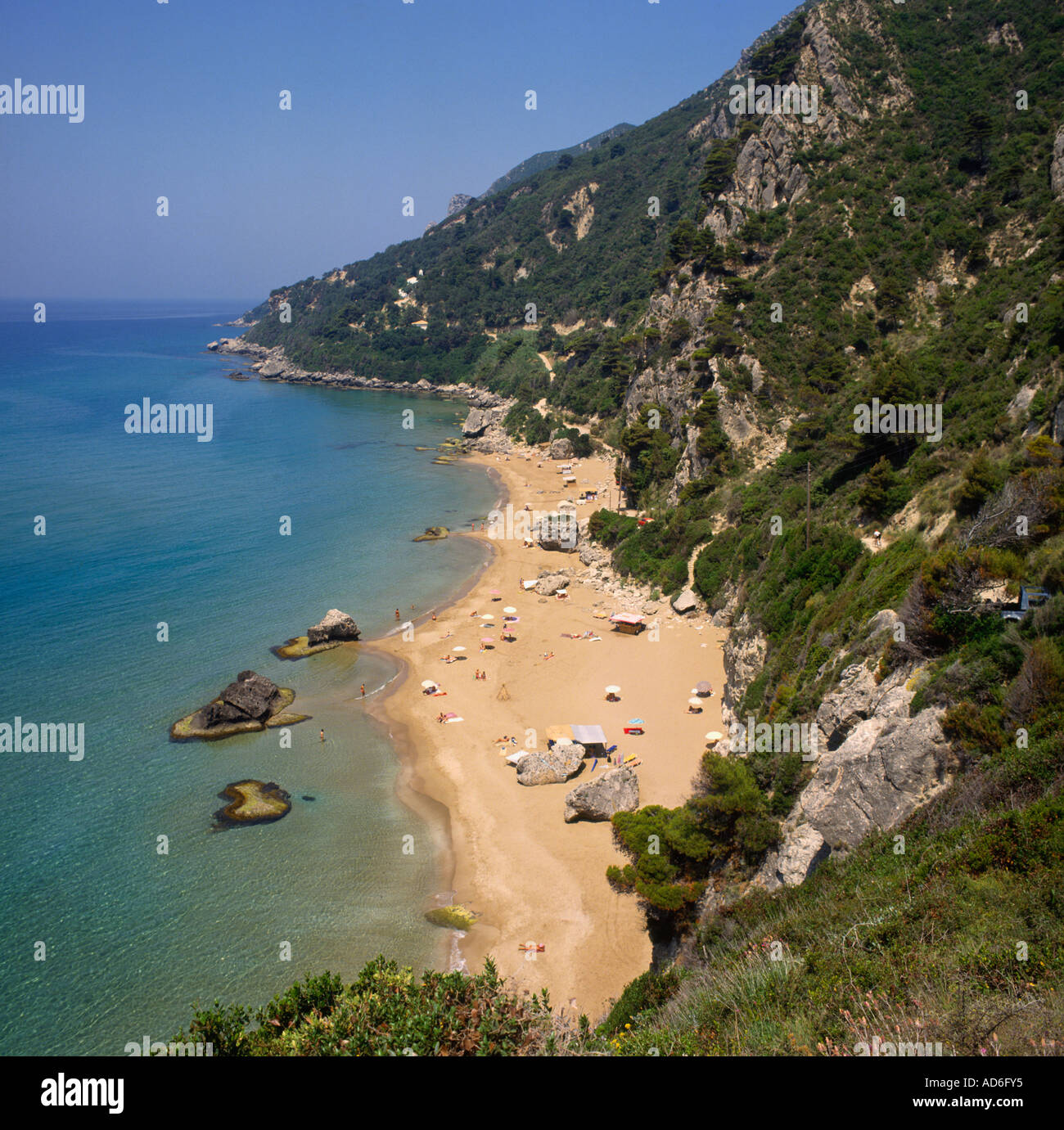 Aerial view looking over sheer tree covered cliffs dropping to sandy ...