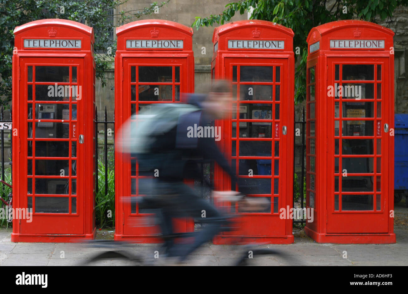 cyclist riding at speed past 4 red telephone kiosks Stock Photo - Alamy