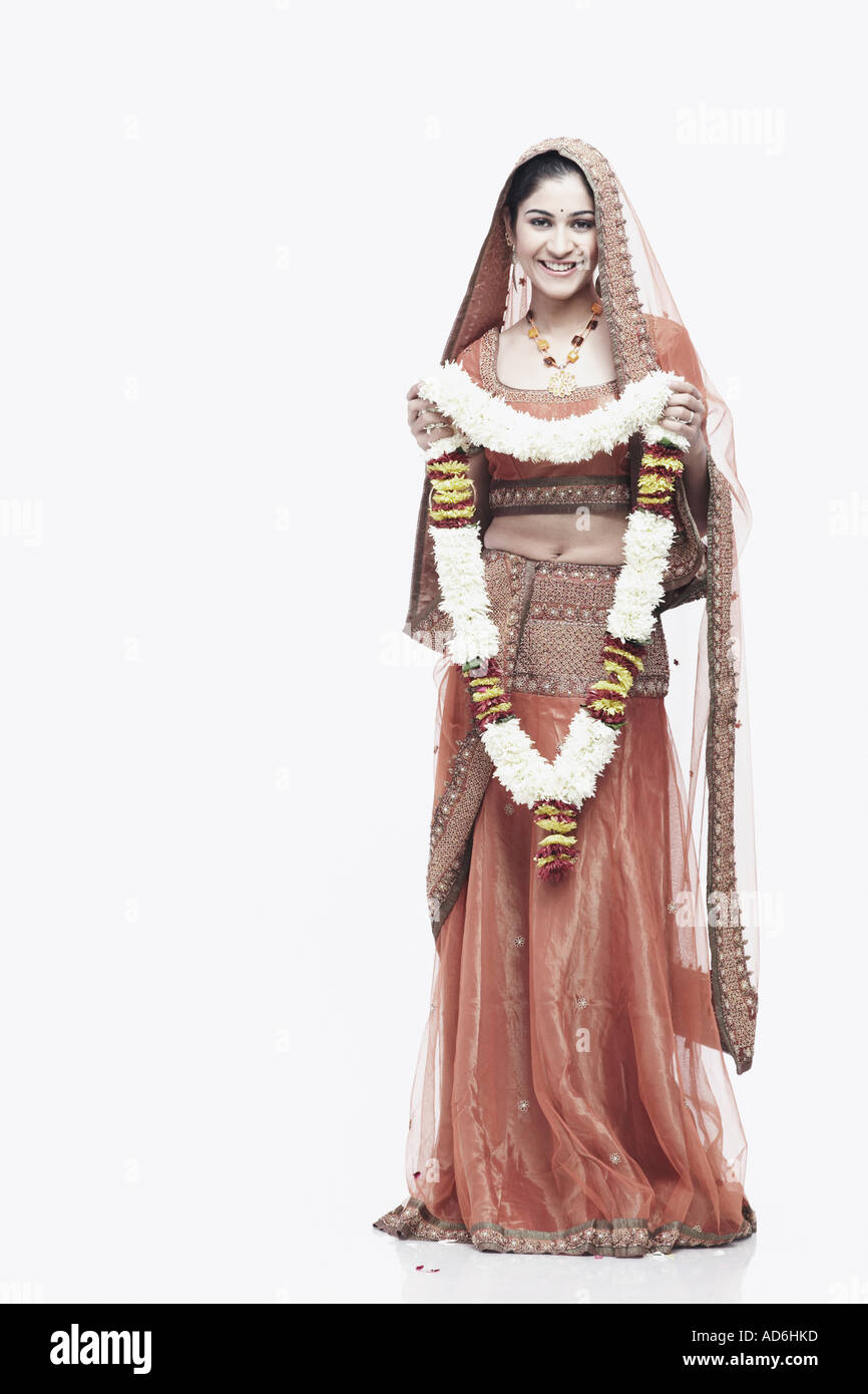 Portrait of a young woman in traditional clothing holding a garland ...