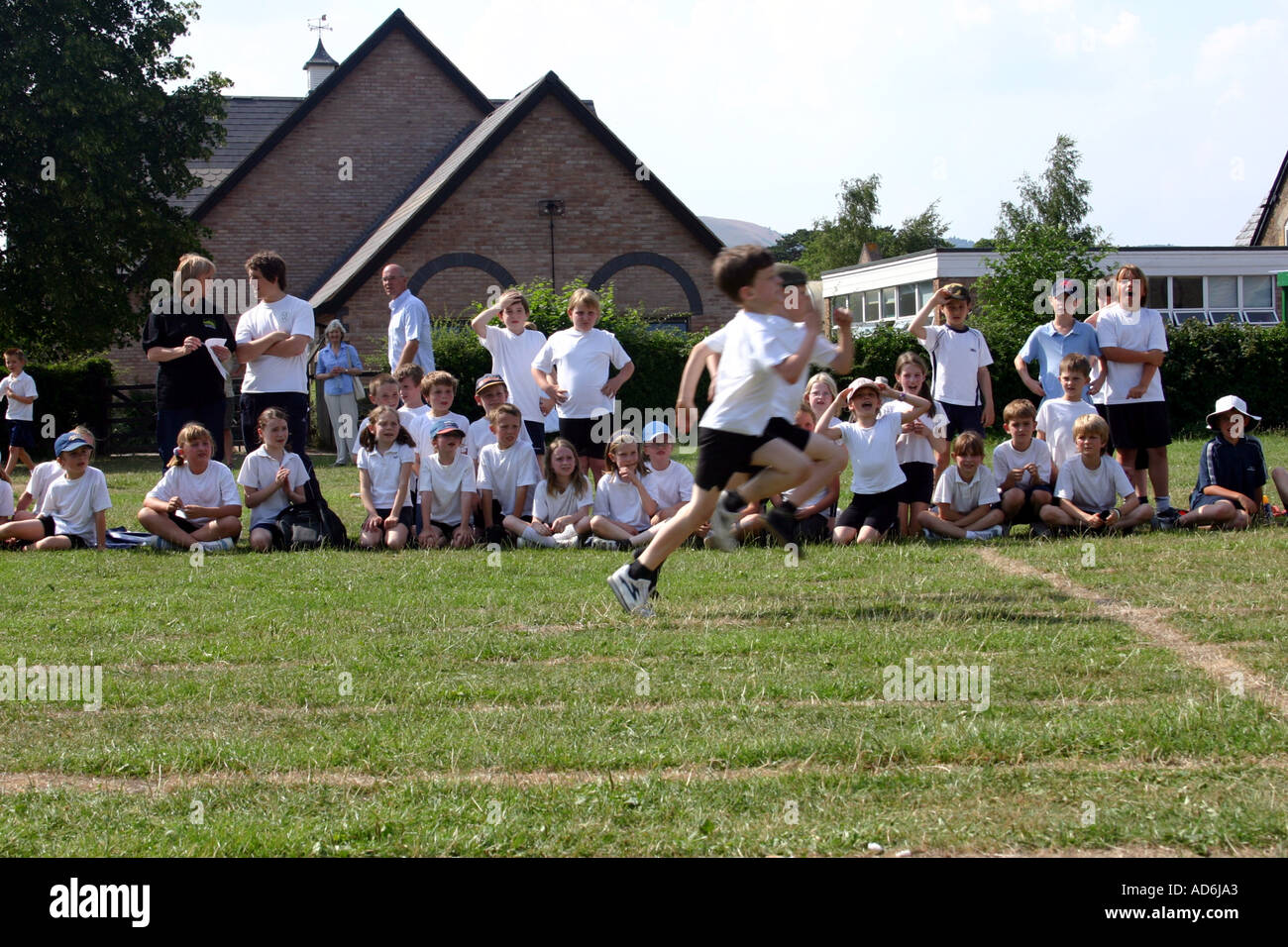 2 boys at finish line of a race on school sports day being cheered on ...