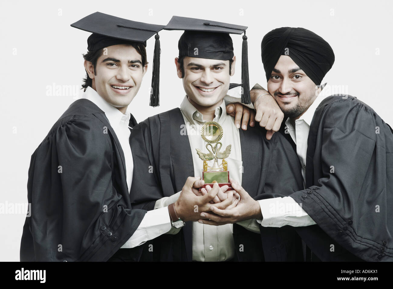 Portrait of three male graduates holding a trophy Stock Photo - Alamy