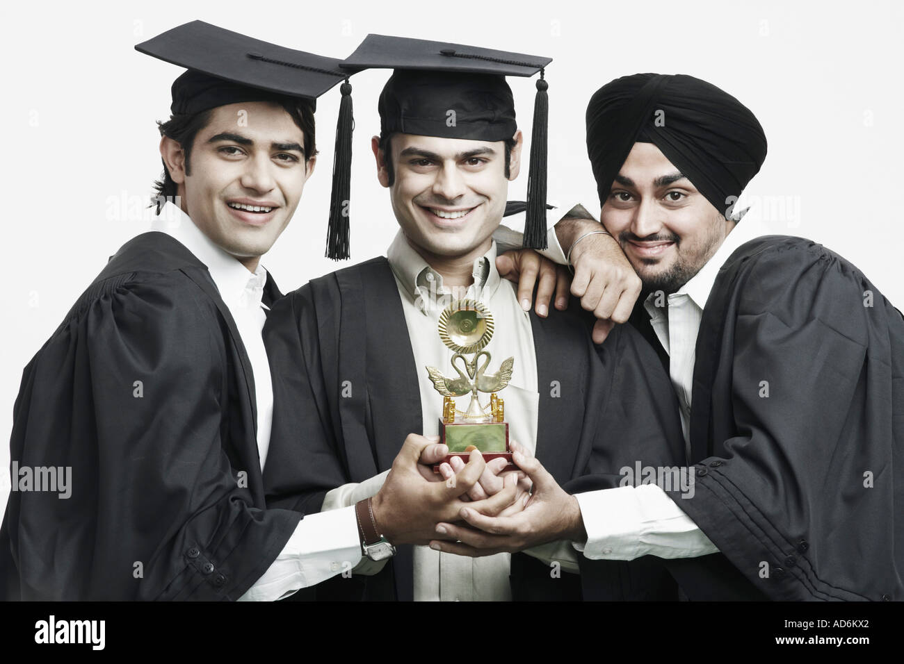 Portrait of three male graduates holding a trophy Stock Photo - Alamy