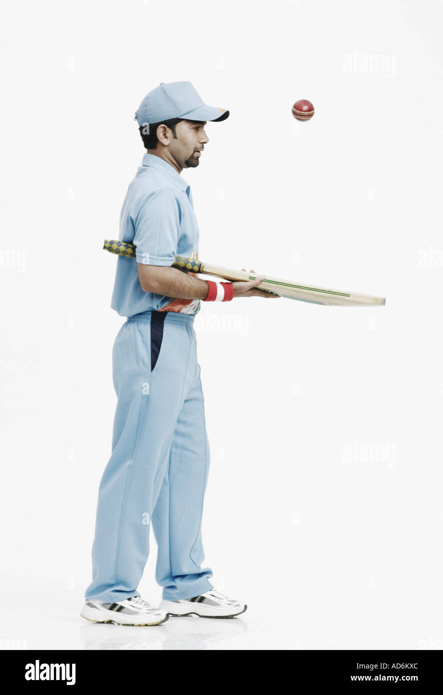 Side profile of a young man playing with a cricket bat and a cricket ...