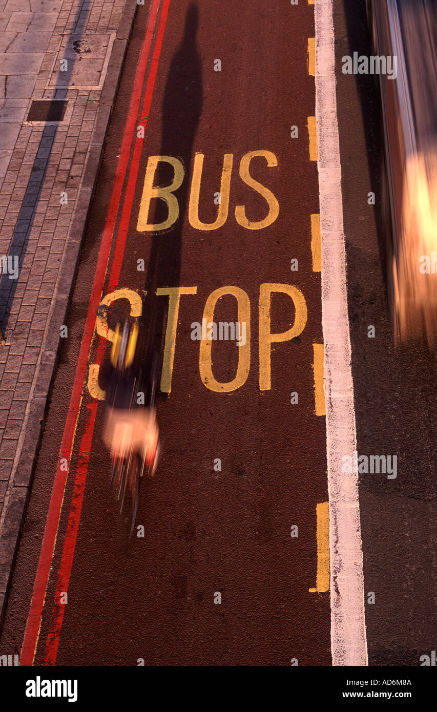 Bus stop cycle lane with cyclist and passing coach in blurred motion in ...