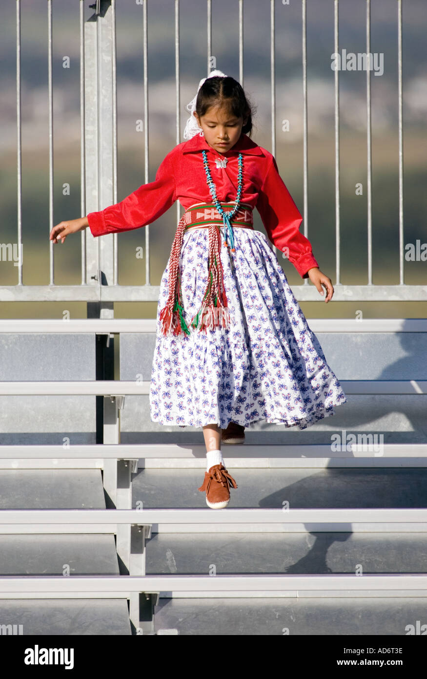 A girl dressed in traditional native american garb plays on bleachers ...