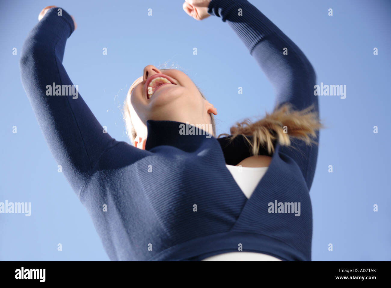 Young woman jumping happily in front of blue sky, view from below Stock ...