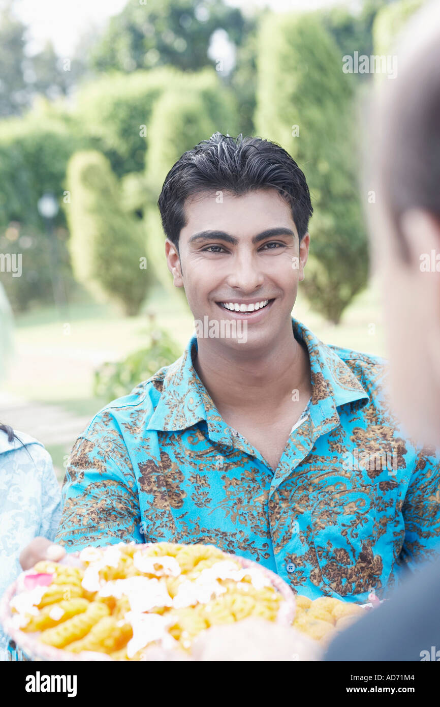 Portrait of a young man holding a dish of Indian sweets smiling Stock ...
