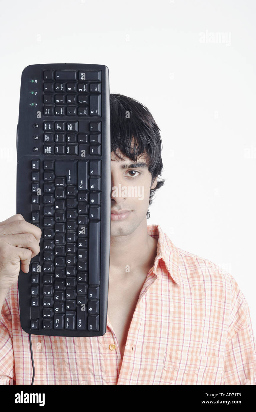 Portrait of a young man holding a computer keyboard in front of his ...
