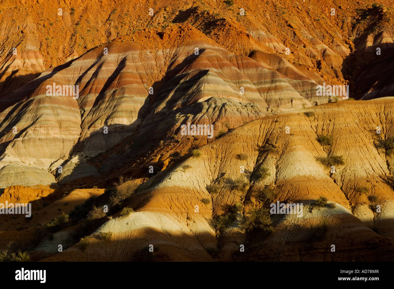 Sunset light on layered sediment rock on eroded hills along the ...