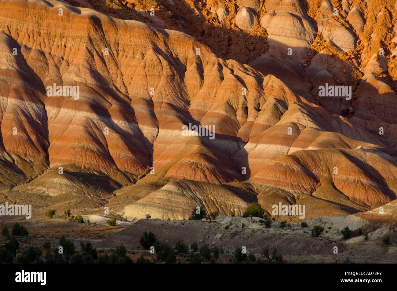 Sunset light on layered sediment rock on eroded hills along the ...
