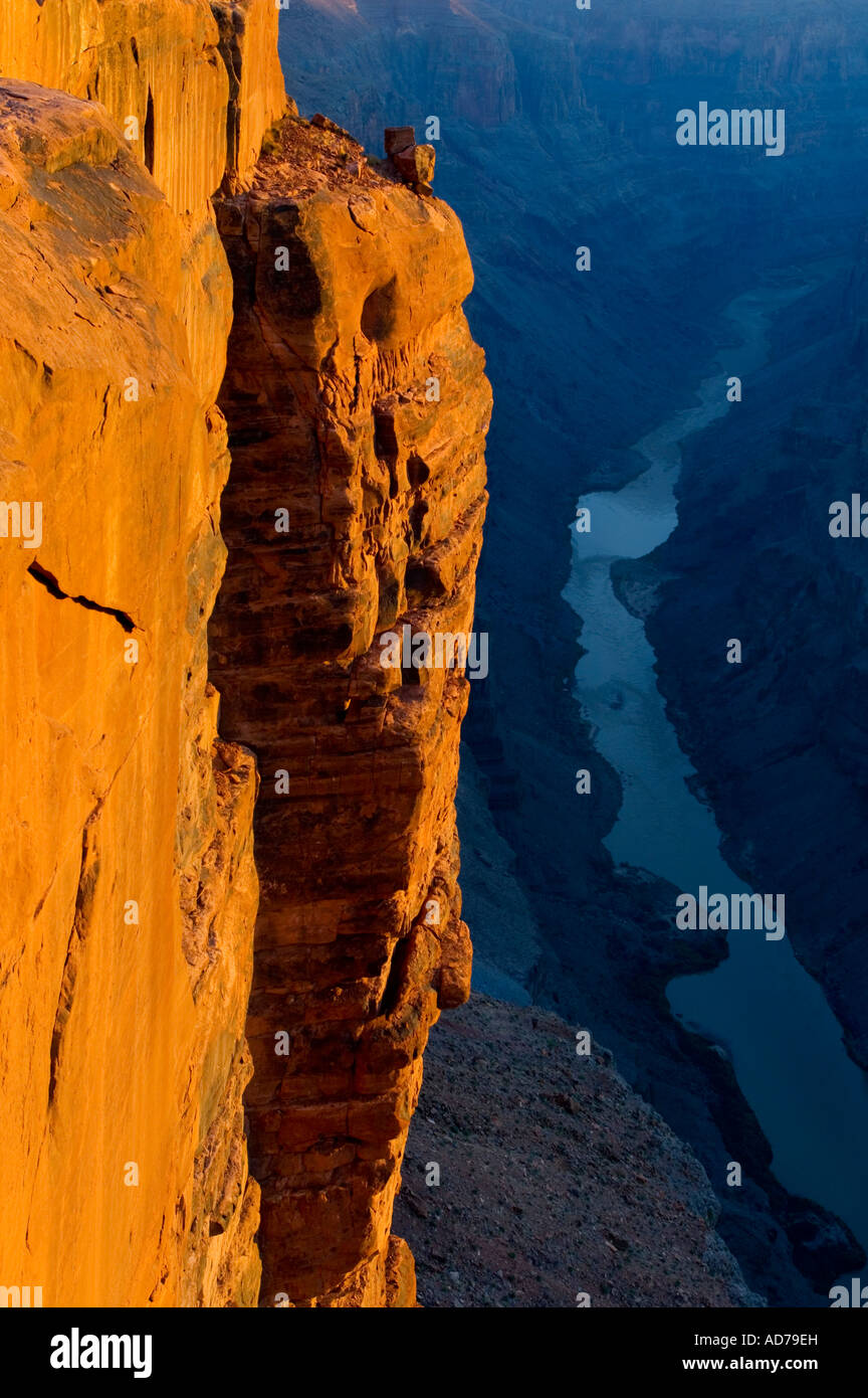 Golden sunrise light on steep sheer rock cliff above the Colorado River ...