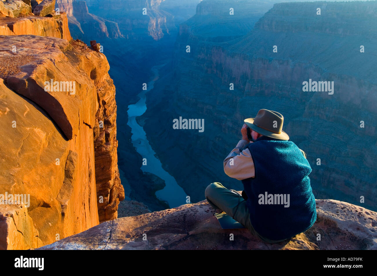 Tourist photographing rock at the edge of a steep cliff above the ...