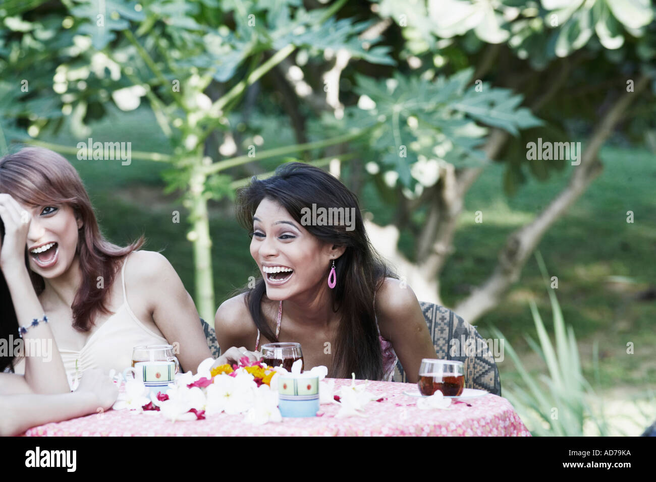 Two young women sitting at a table and laughing Stock Photo - Alamy