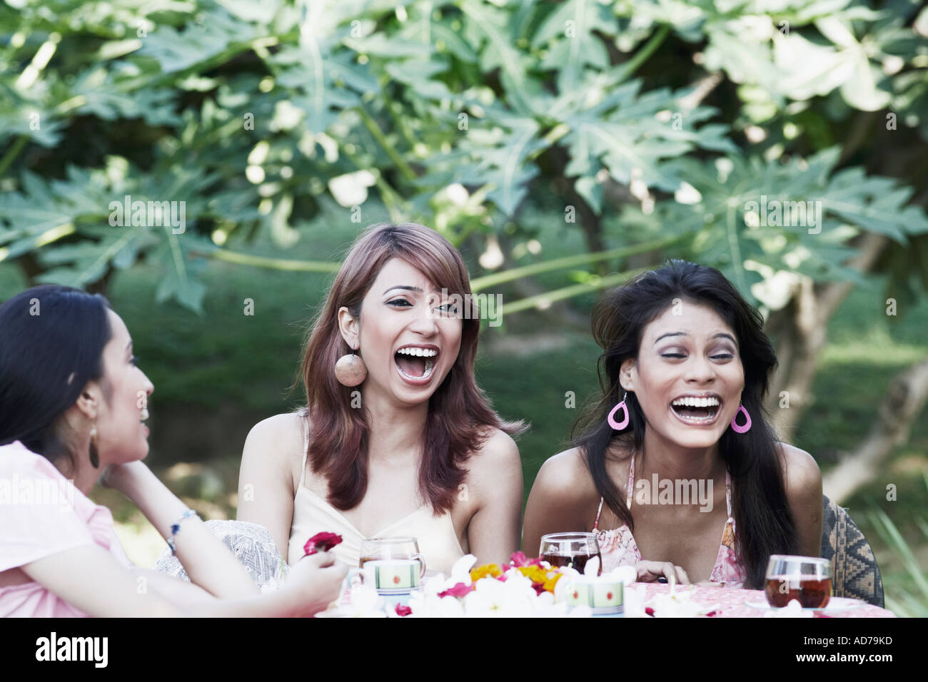 Two young women and a teenage girl sitting at a table and laughing ...