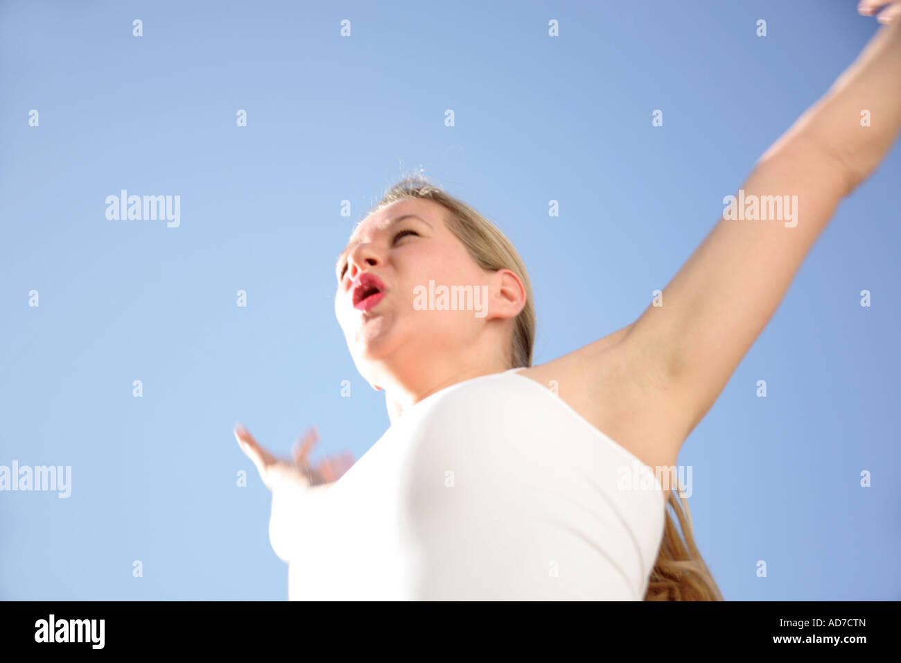 Woman stretching out arms in front of blue sky, low angle view Stock ...