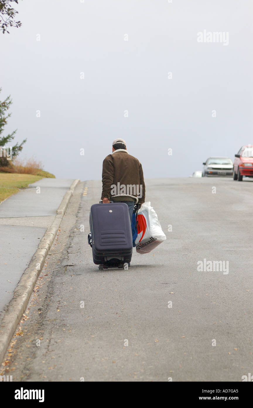 Person walking up a steep hill pulling a heavy suitcase Stock Photo - Alamy