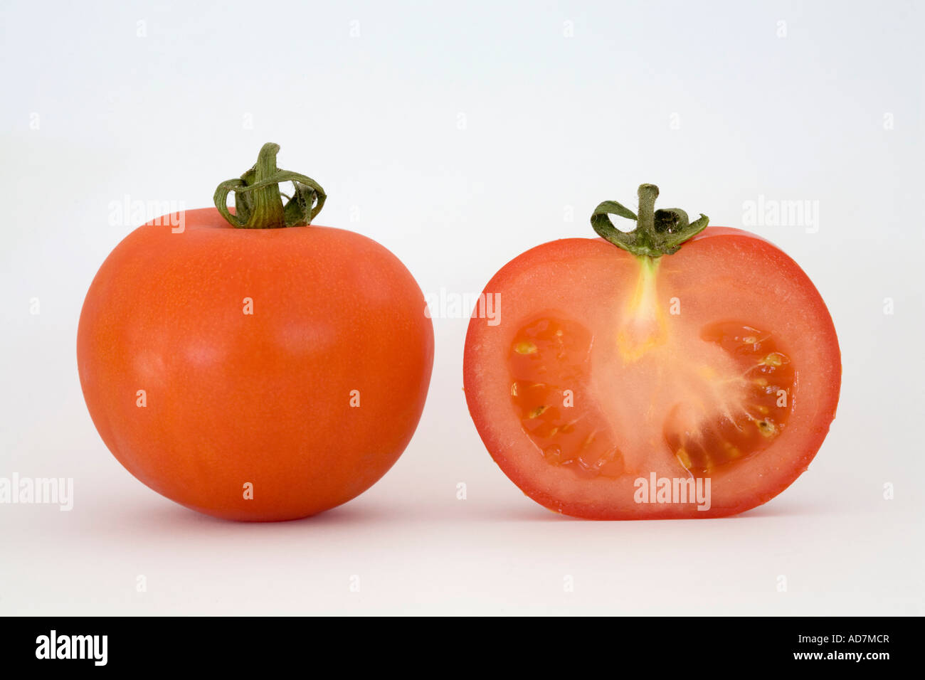 One whole and one halved tomato on white background Stock Photo - Alamy