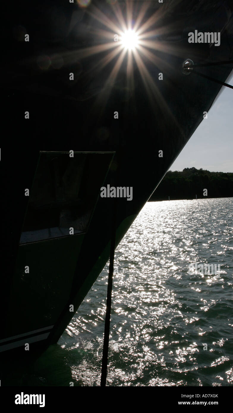 Glare of a setting sun shining through the bow of the hull of a moored ...