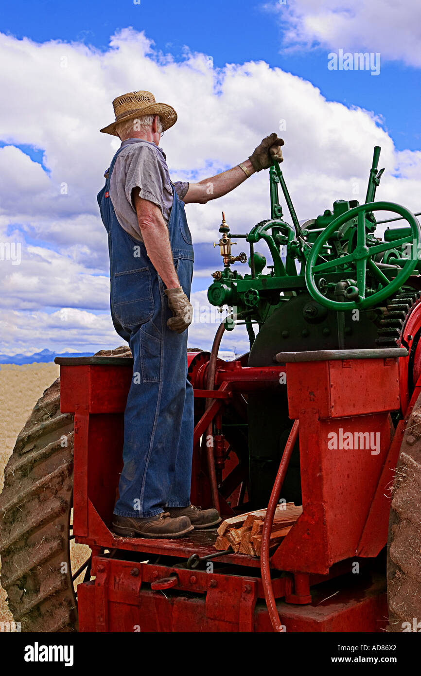 Photo of an elderly farmer standing and working on a tractor Stock ...
