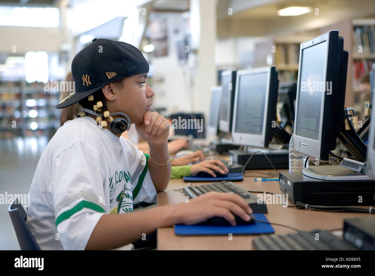One teenage boy behind a computer in the library Stock Photo - Alamy