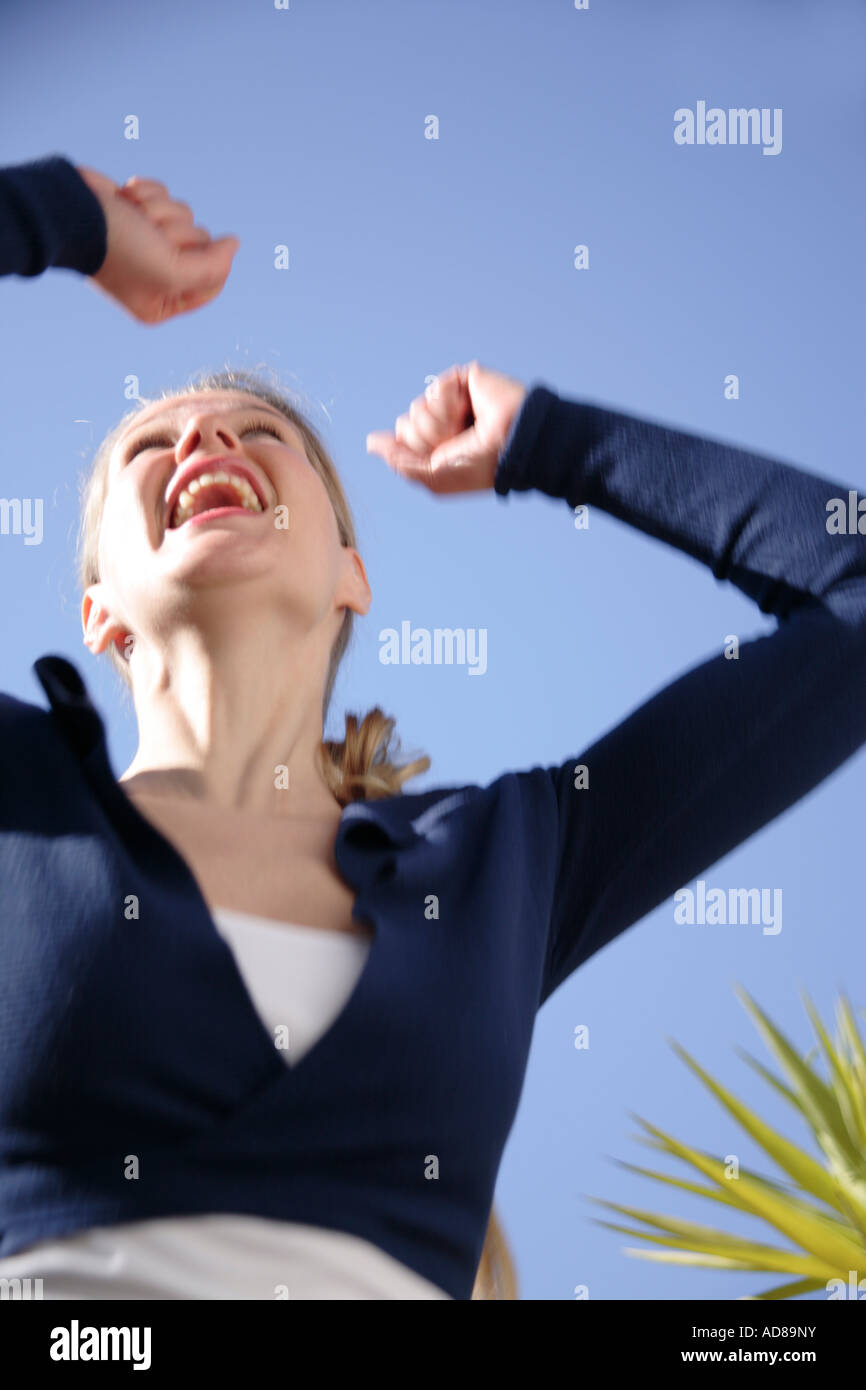 Young woman jumping happily in front of blue sky, view from below Stock ...