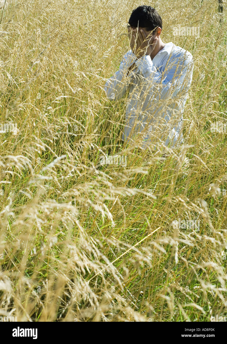 Man standing in field, covering face Stock Photo - Alamy