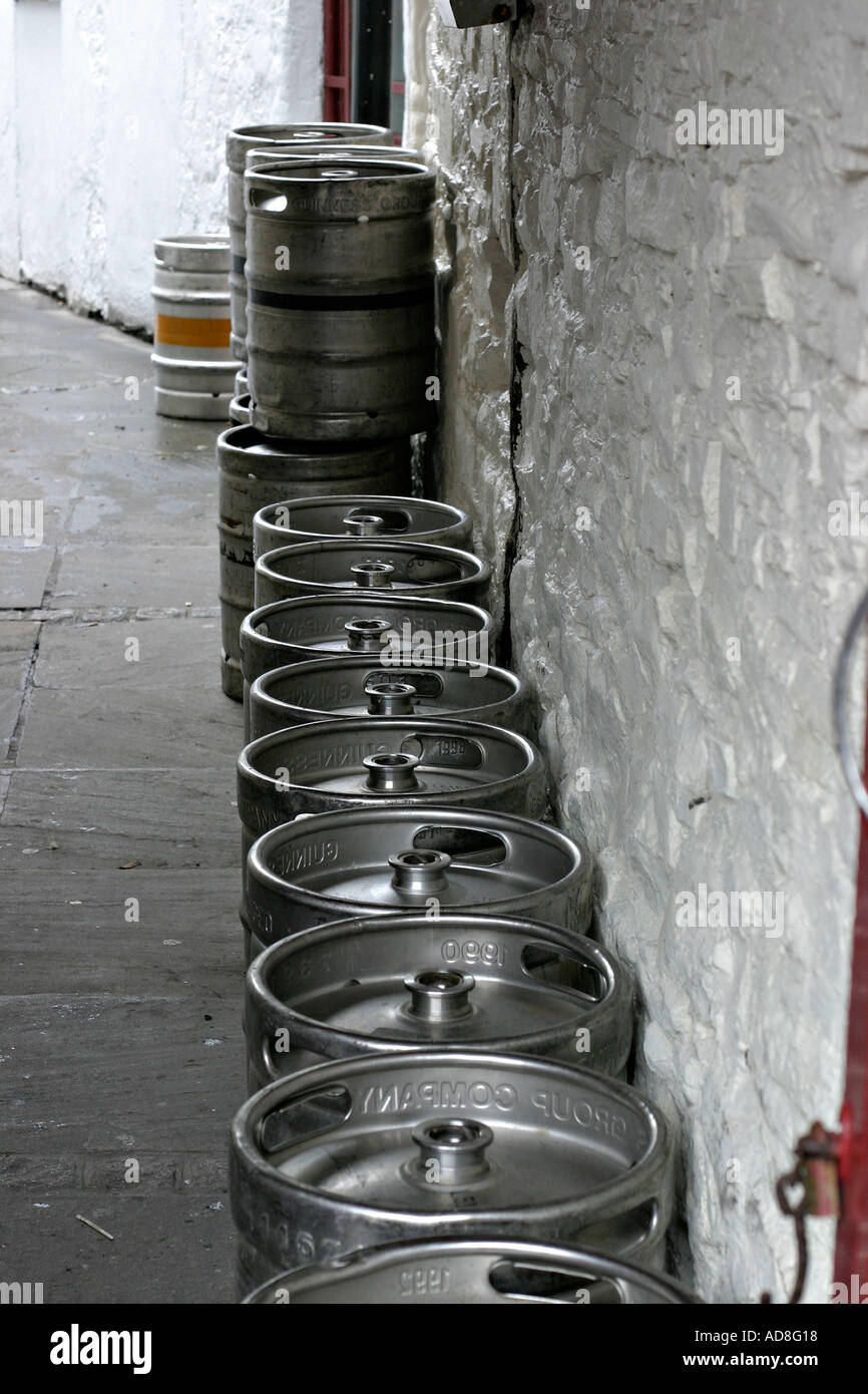 A line of empty aluminum beer kegs against a white stuccoed wall of a ...