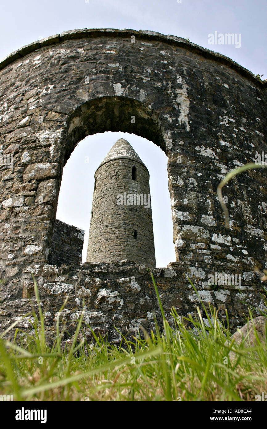 An old stone round tower is framed by the curved altar window of an old ...