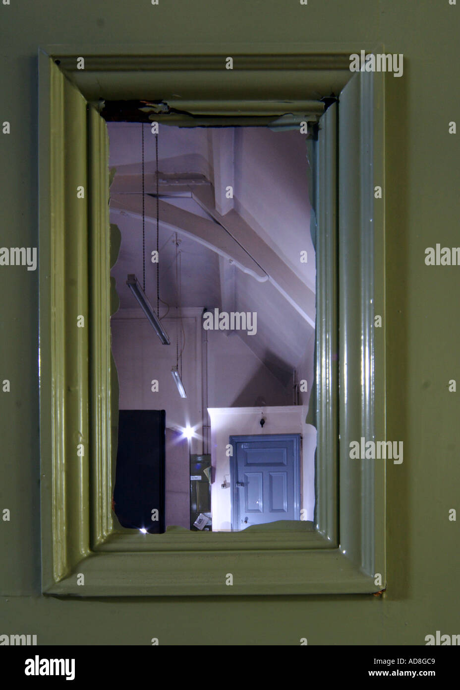 Looking through the broken panel of a door into another room with cold ...