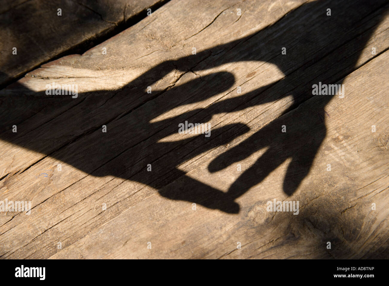 Male hands casting shadow over wooden table Stock Photo - Alamy