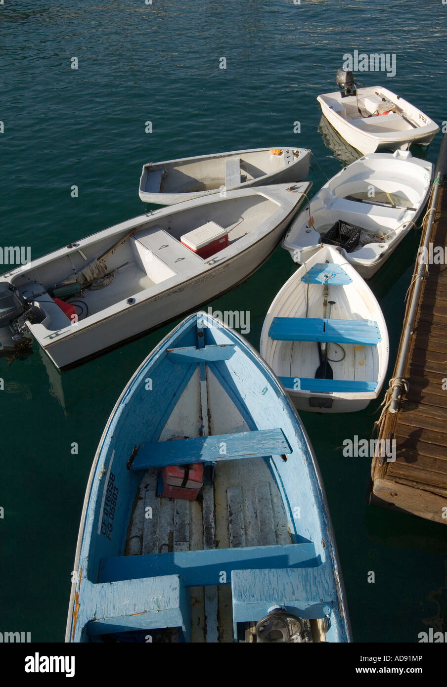 A group of small wooden boats are tied together next to a dock Stock ...