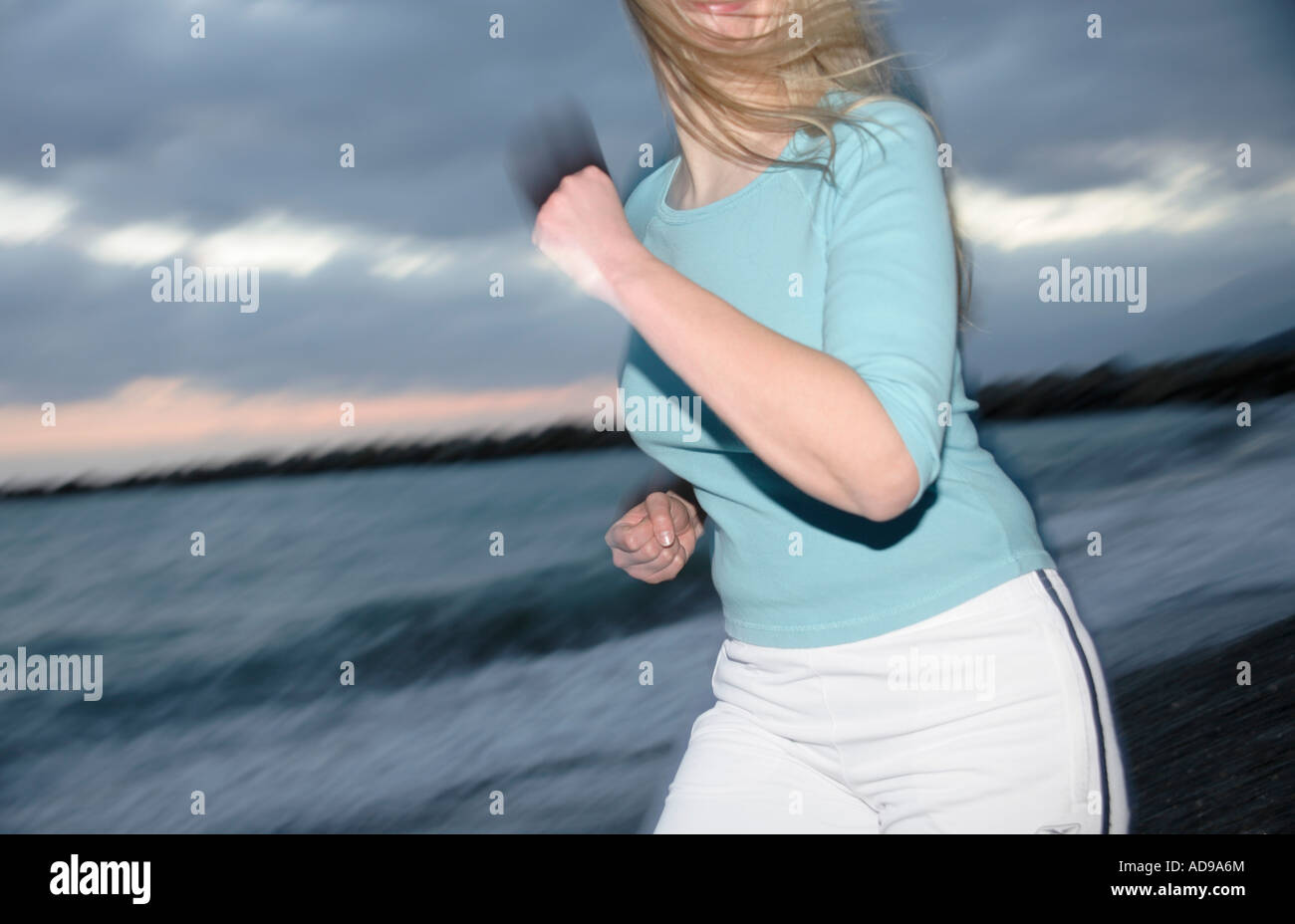 Upper part of woman's body jogging at the beach, side view Stock Photo ...