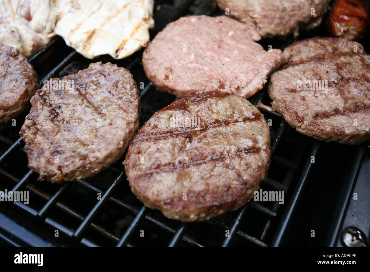 Various meats being cooked on a gas powered barbecue Stock Photo - Alamy