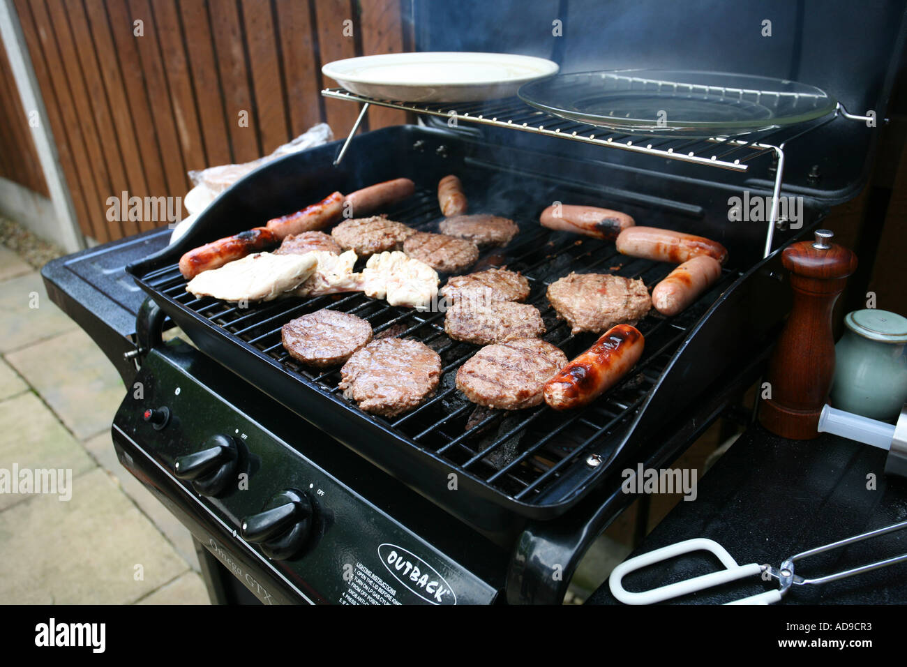 Various meats being cooked on a gas powered barbecue Stock Photo - Alamy
