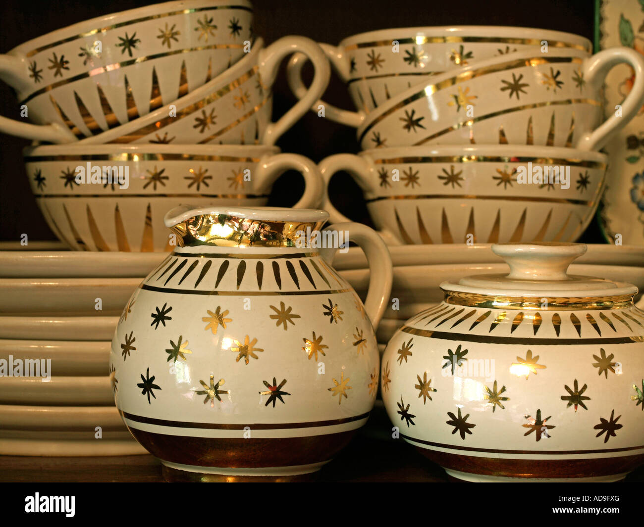 gold pattern crocery tea cups in style of the fifties in a cupboard ...