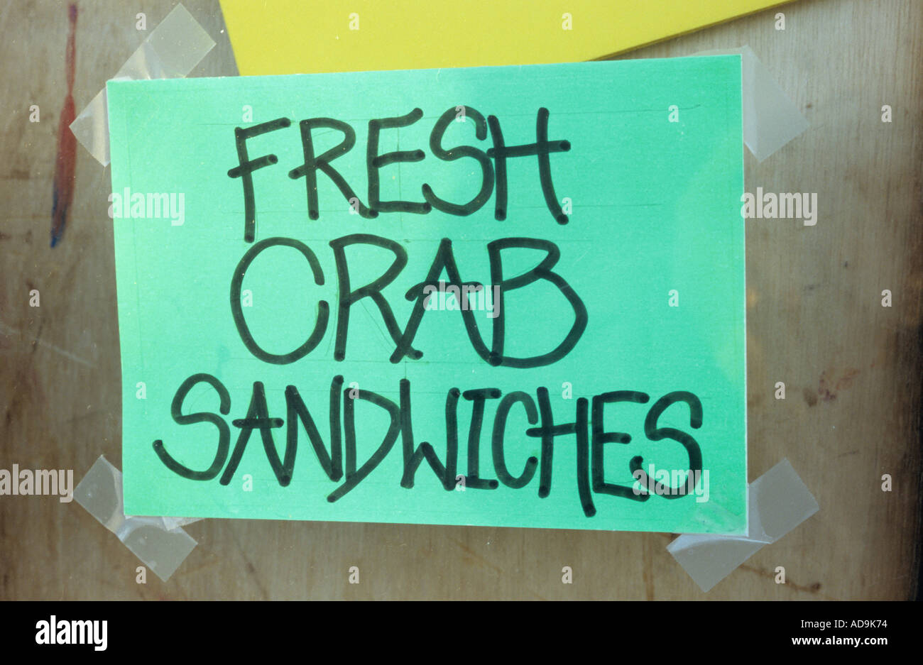 Neatly handwritten sign stuck to a window stating Fresh crab sandwiches ...