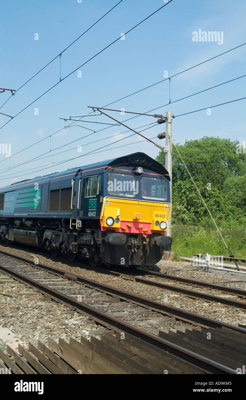 Freight train approaching a level crossing where a country lane crosses ...