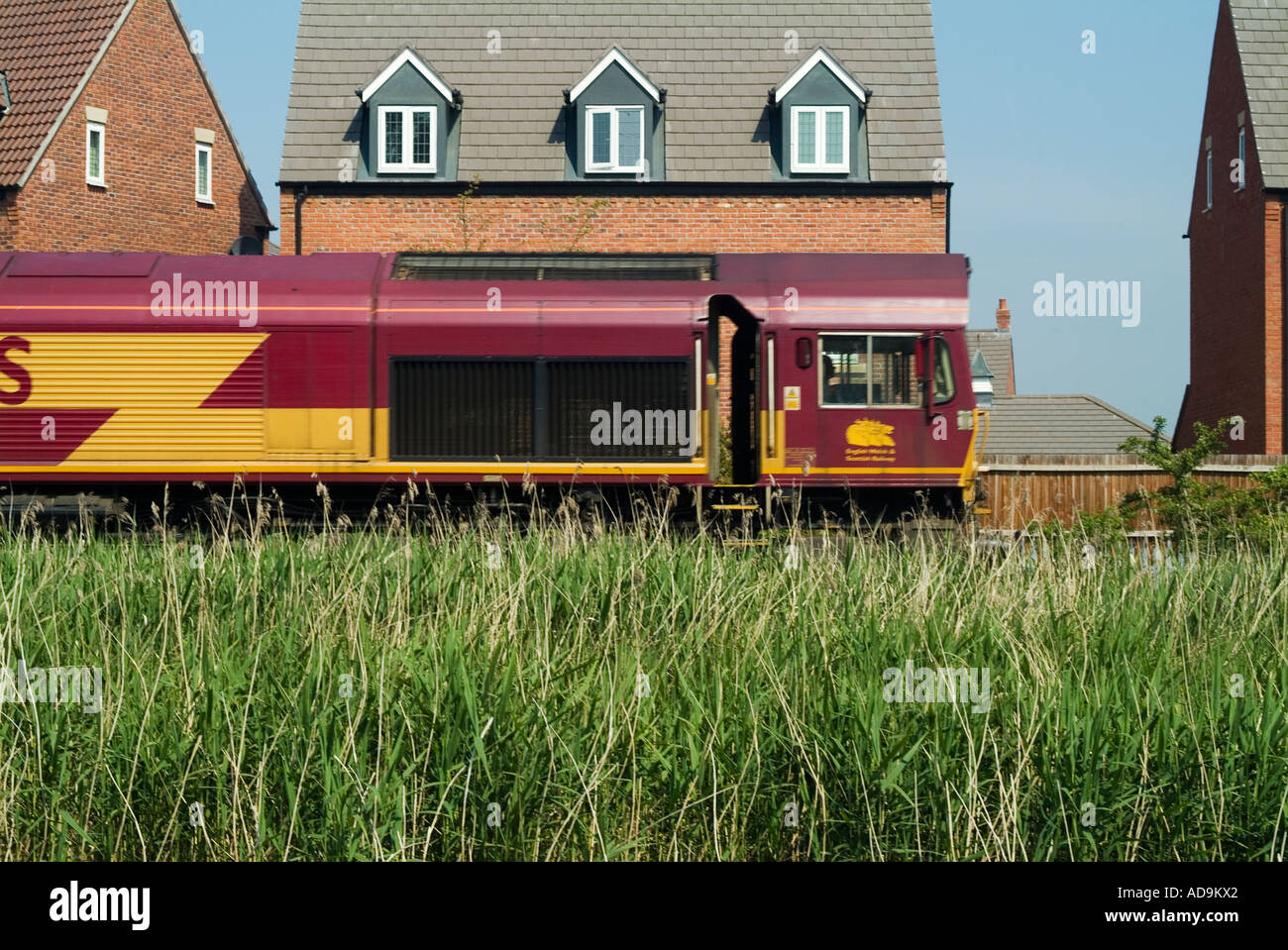 Freight train passing close to a new housing estate Stock Photo - Alamy