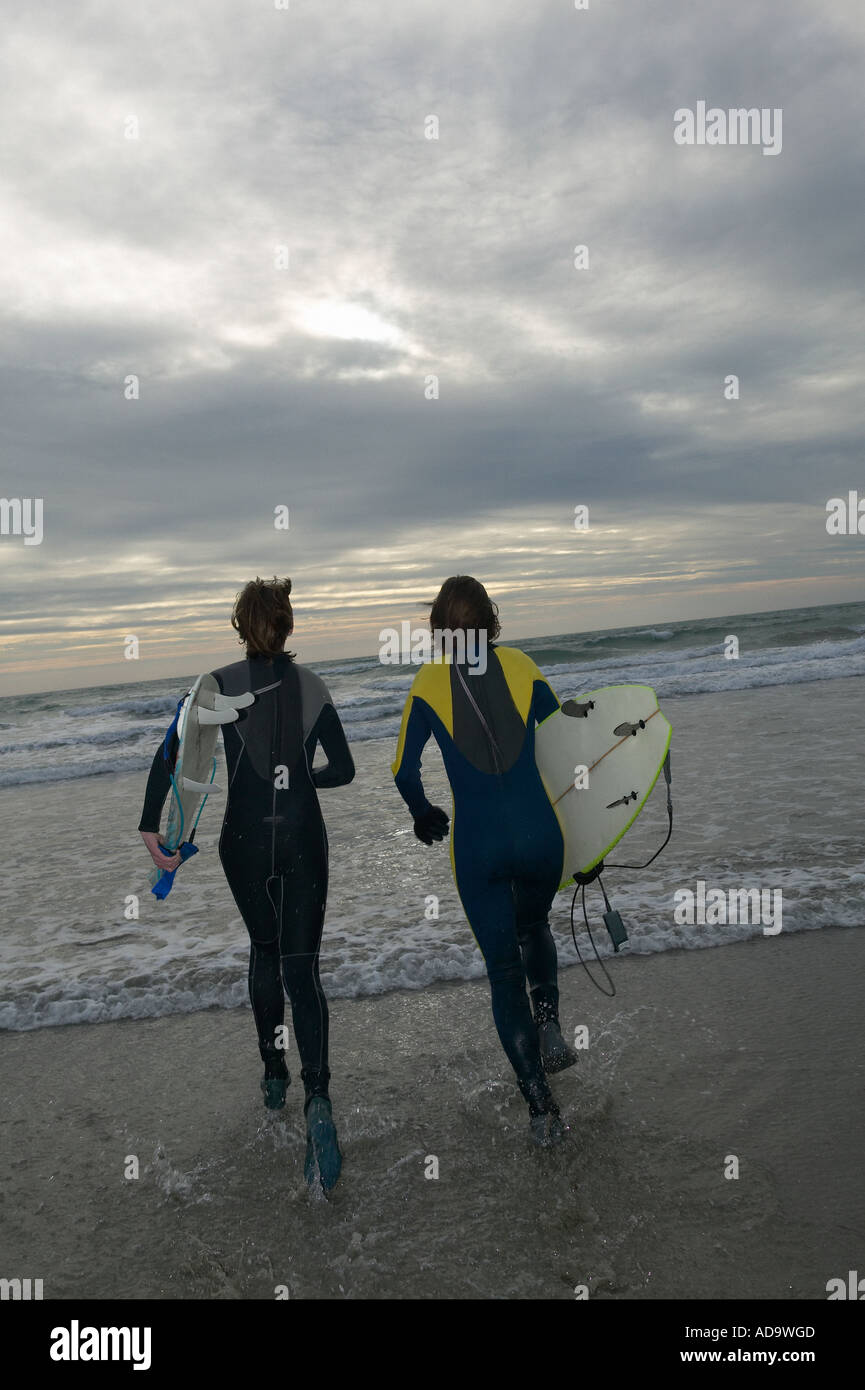 Two young surfers running to the water with their board Stock Photo - Alamy