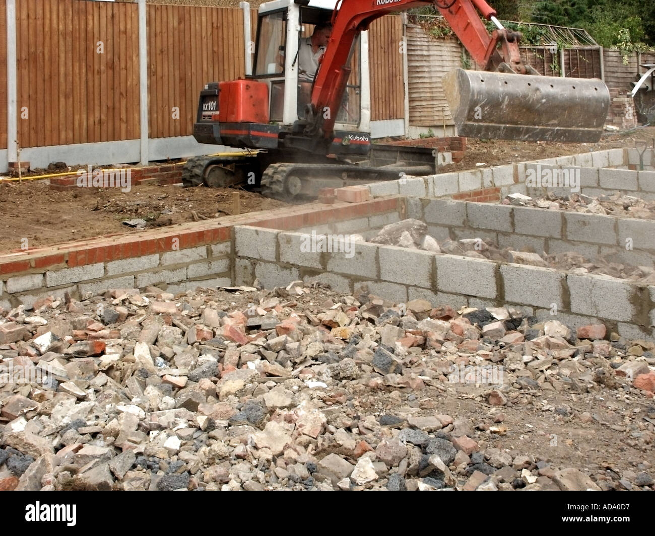 Mini Digger hydraulic excavator & driver placing hardcore rubble to ...