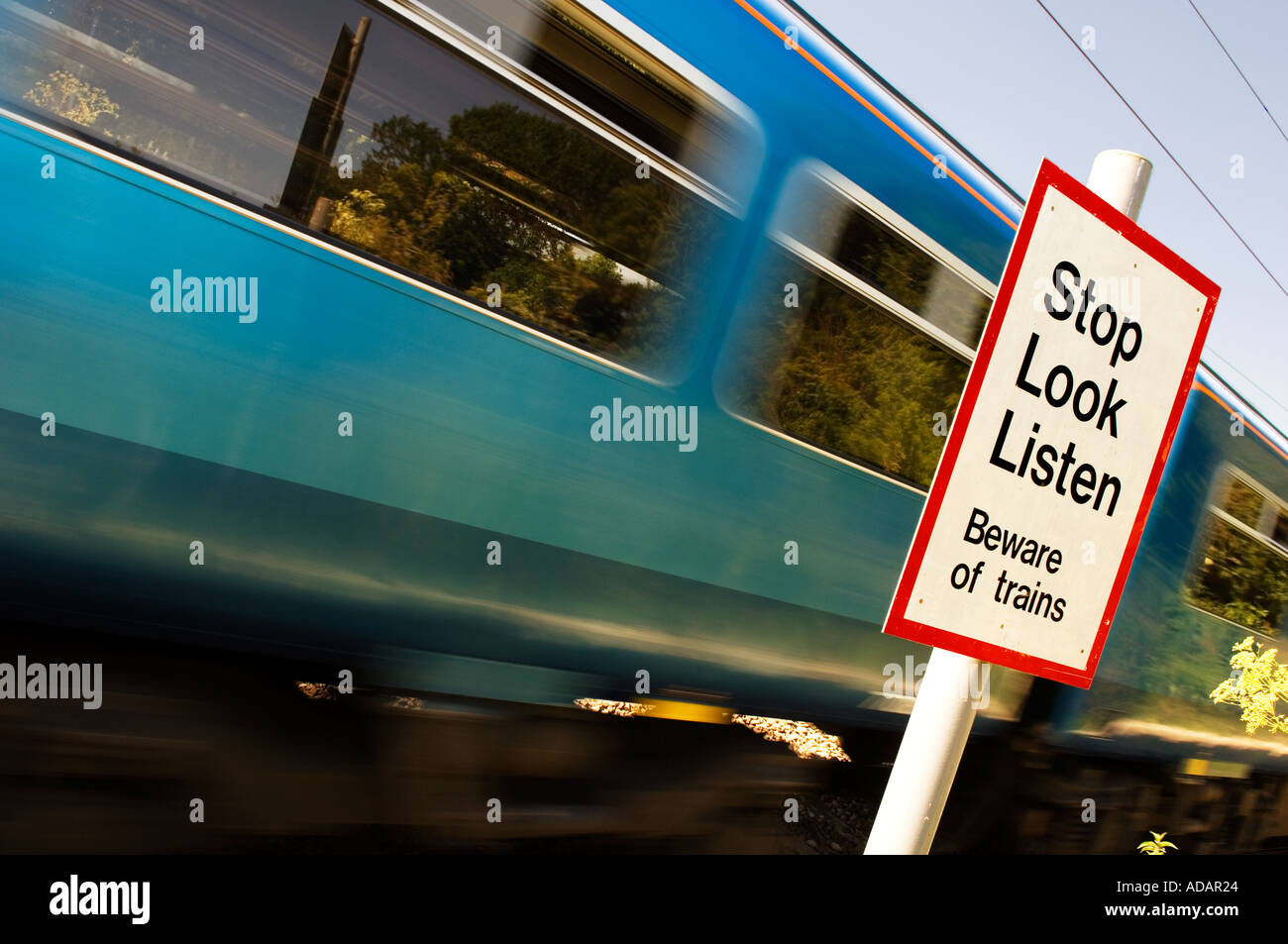 Train speeding through a pedestrian rail crossing with warning sign ...