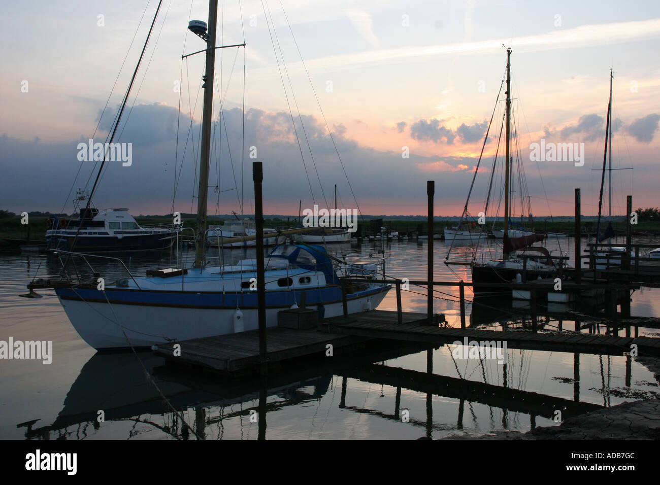 Late evening view across river with jetties and boats reflecting in ...