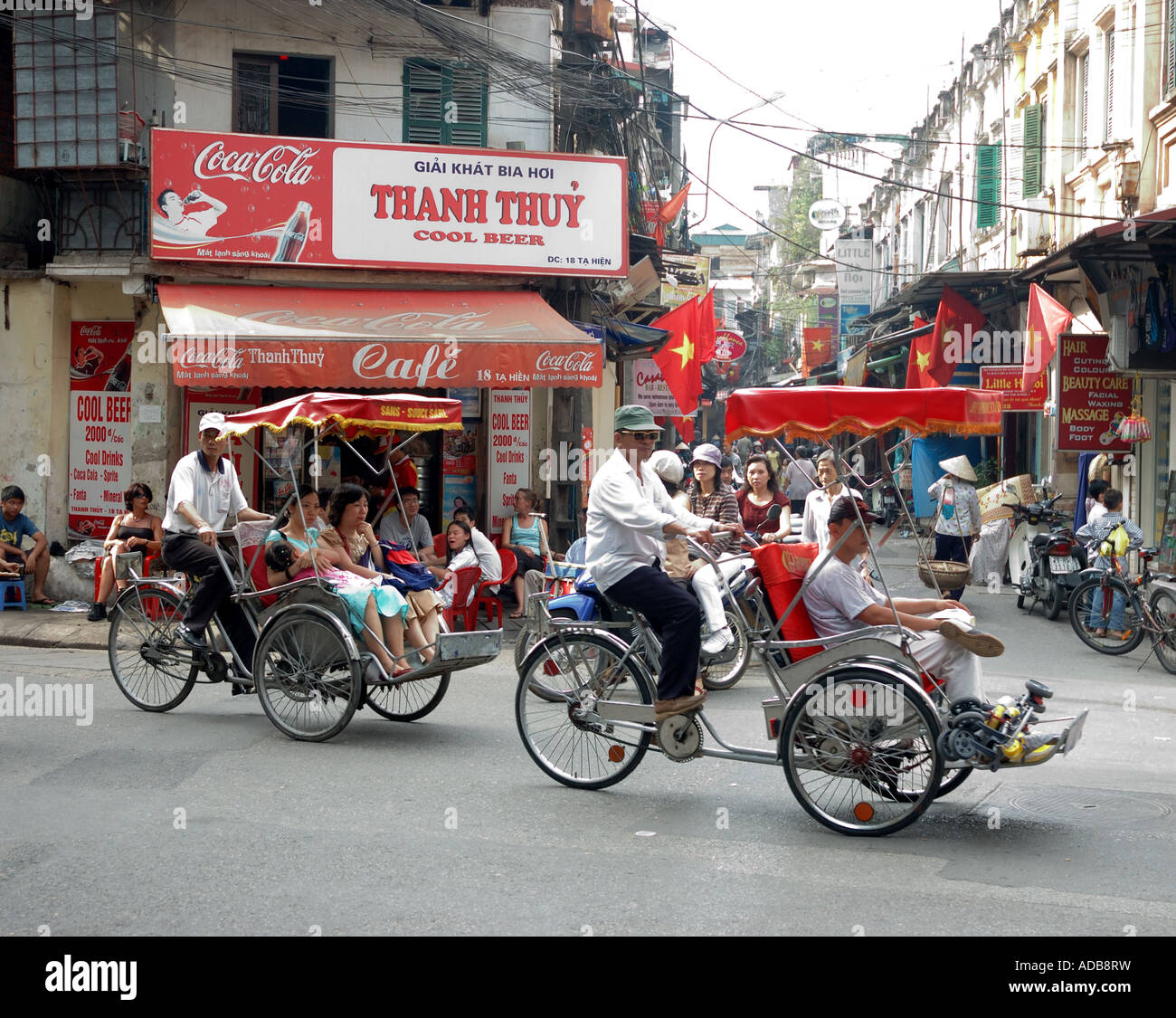 Two rickshaws with passengers on busy street corner of beer street in ...