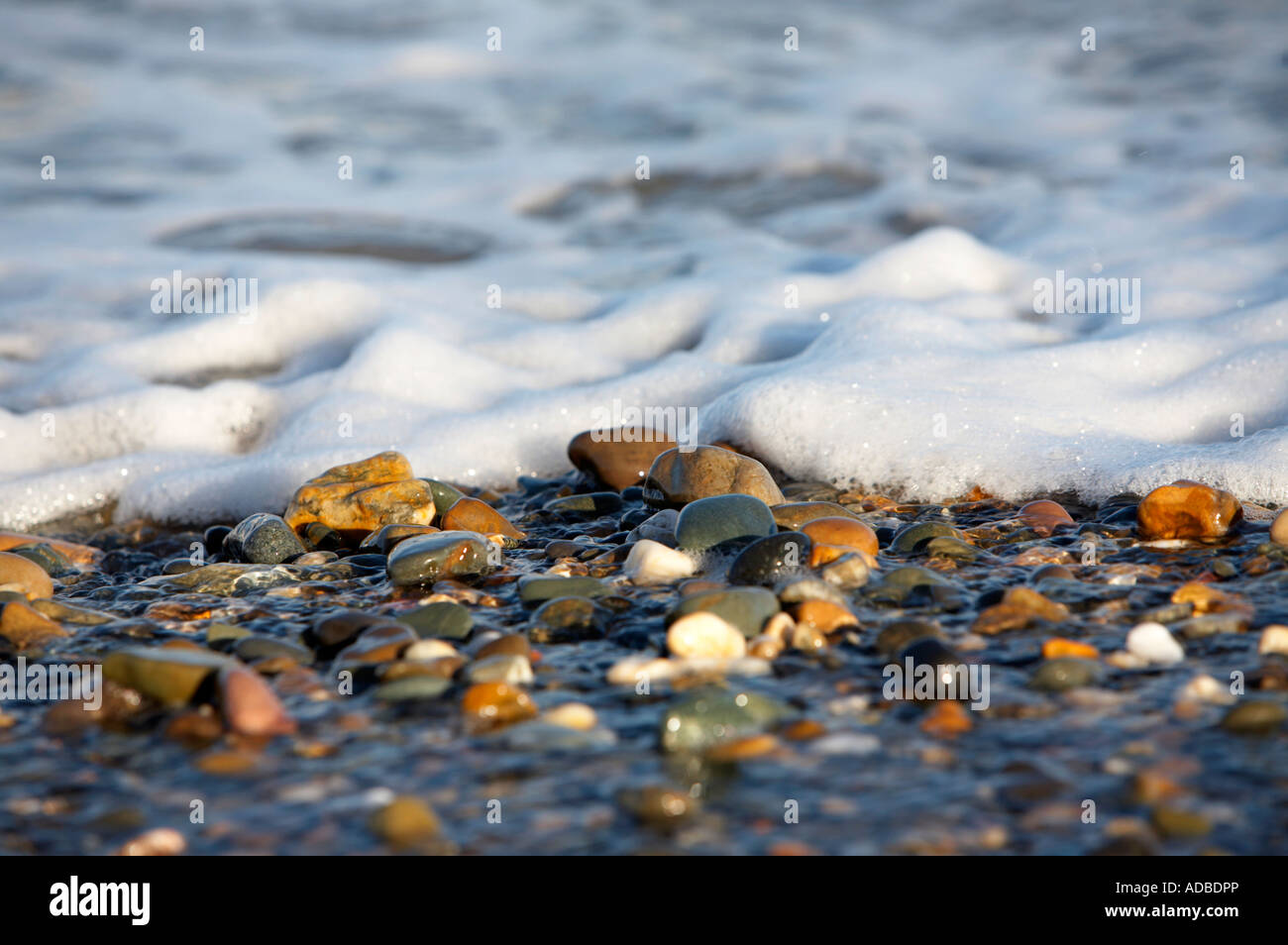A wave washing over stones pebbles on beach hi-res stock photography ...