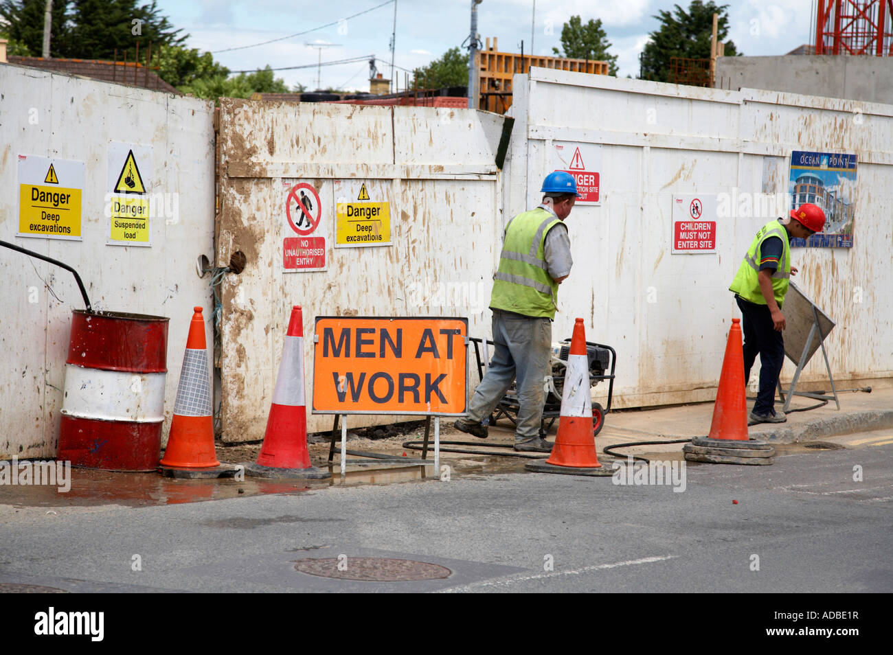 two workers in safety helmets and hi vis vests adjust traffic diversion ...