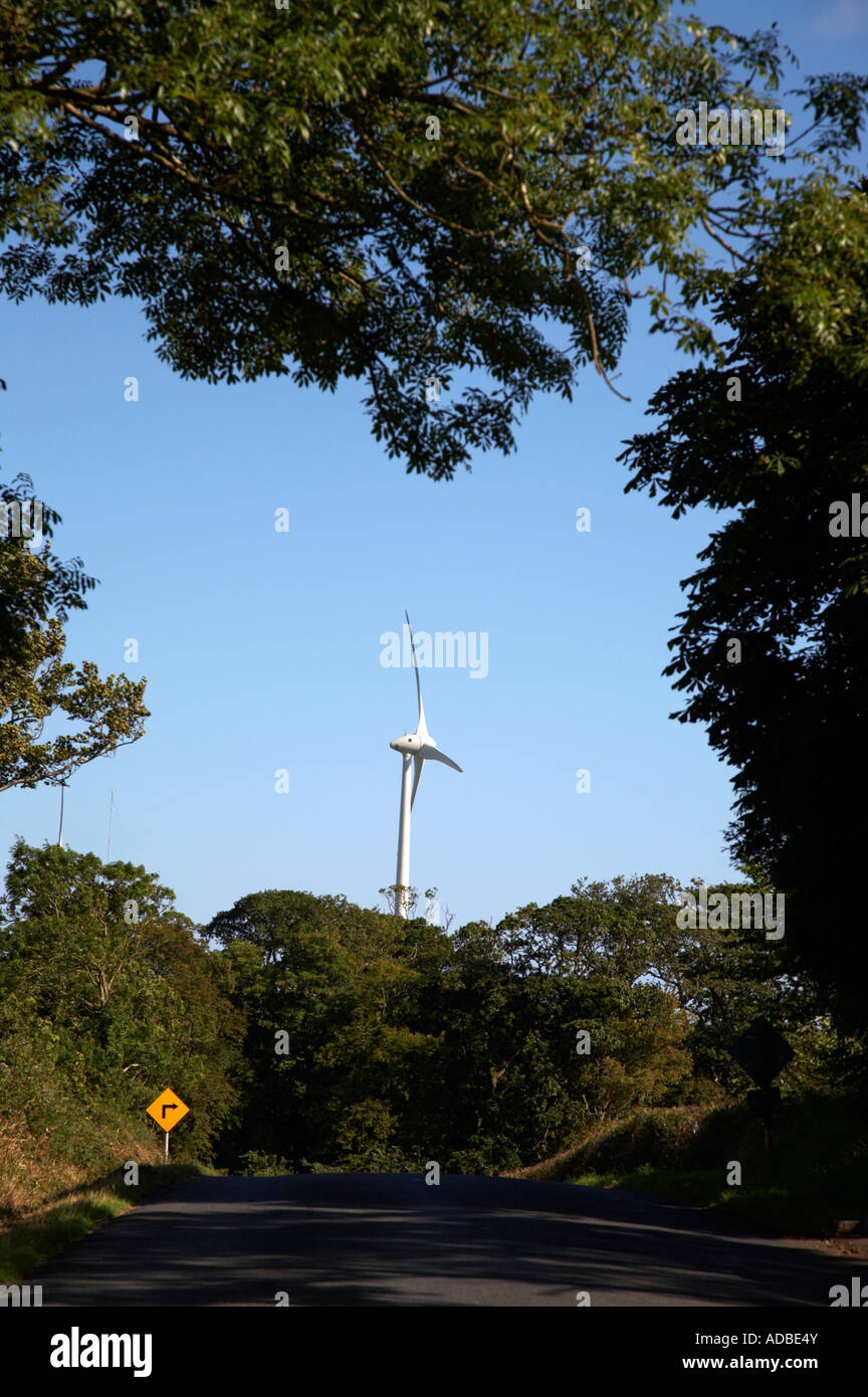 country lane with sharp turn sign with wind turbine in the distance ...